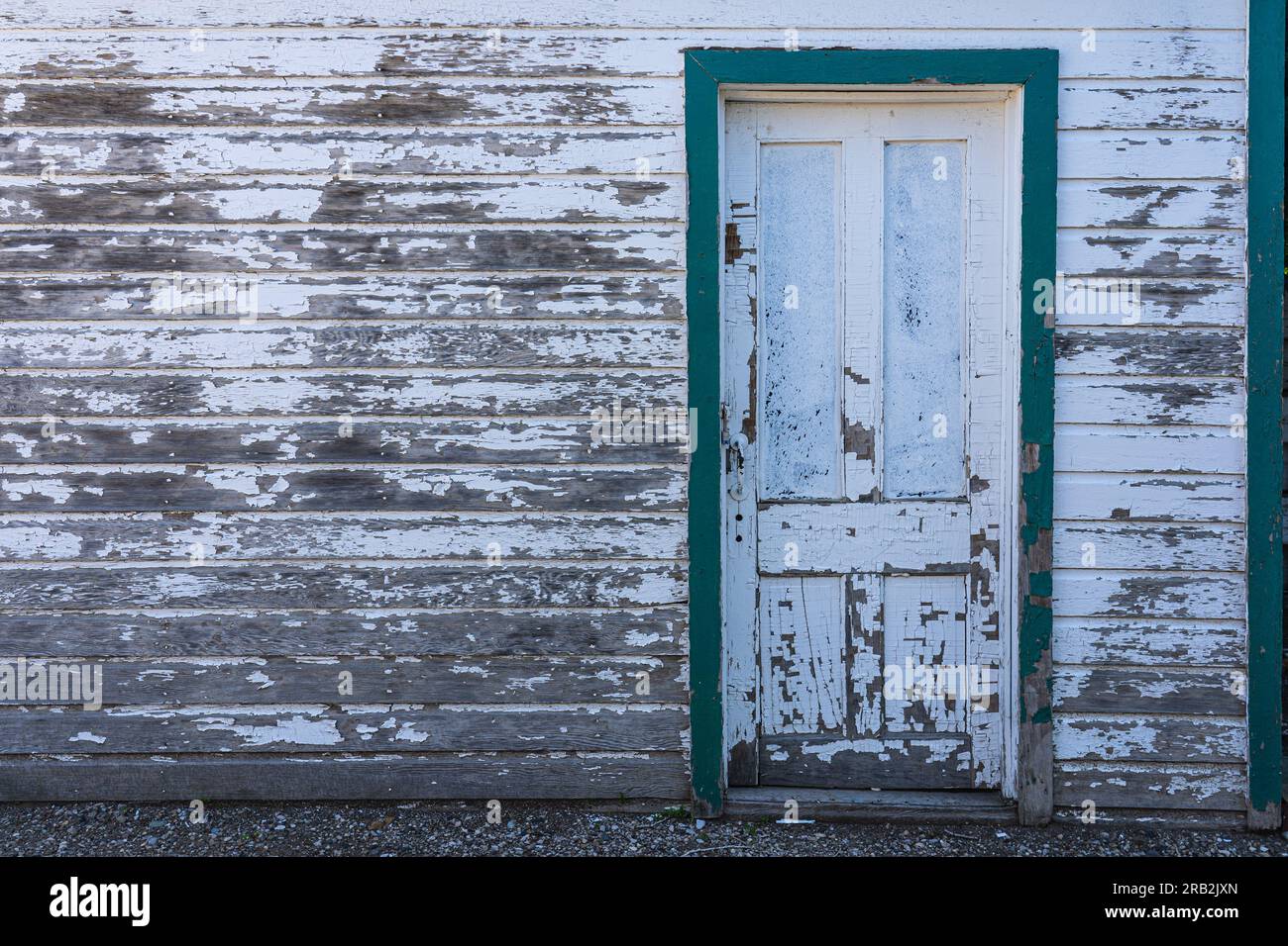 Green & white old vintage building shows signs of weathering & paint peeling.. Door is closed ...