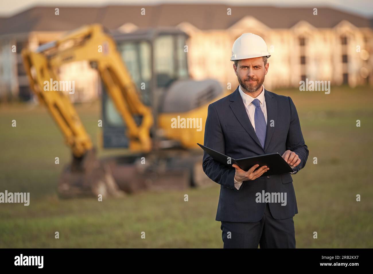 Architect at a construction site. Architect man in helmet and suit at ...