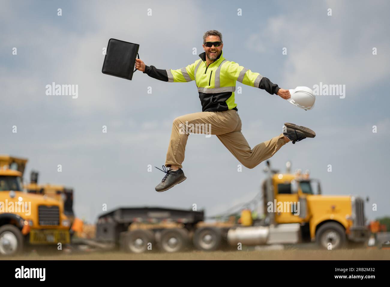 Builder excited jump with hardhat helmet on construction site ...