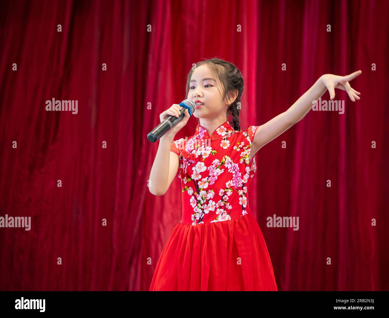 The Asian kid girl sing a song on stage at her school activity day ...