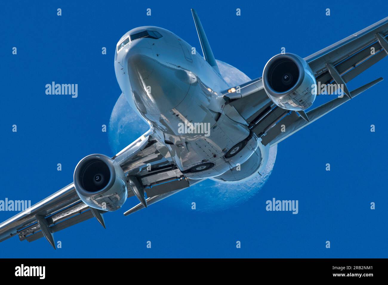 Sharp, close-up telephoto image of jet aircraft inflight with full moon ...