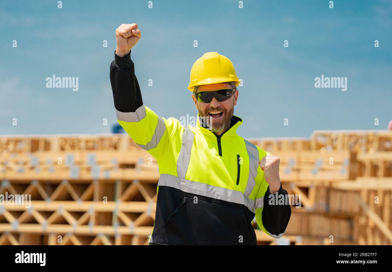 Excited foreman in hard hat at new house under construction. Builder on ...