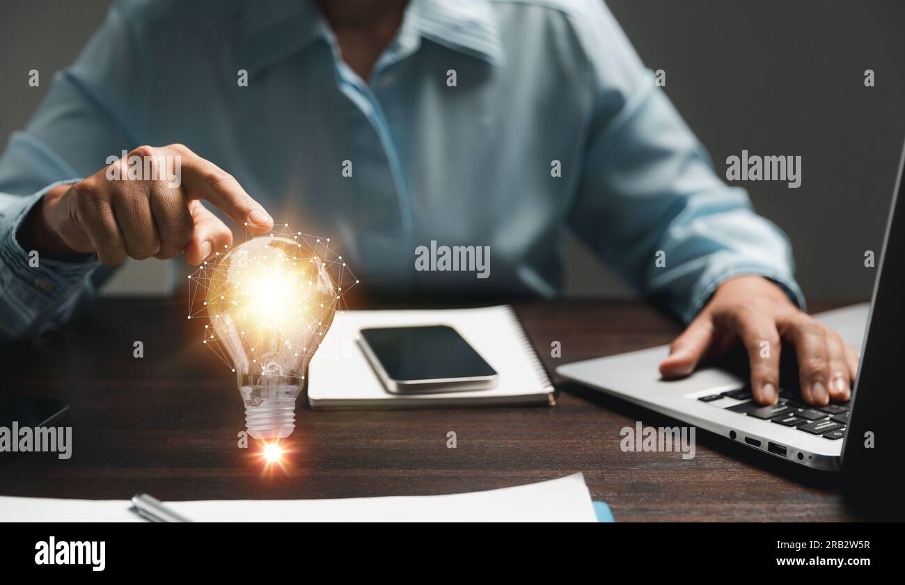 Hand of woman with light bulb and there is gear icon and using laptop ...