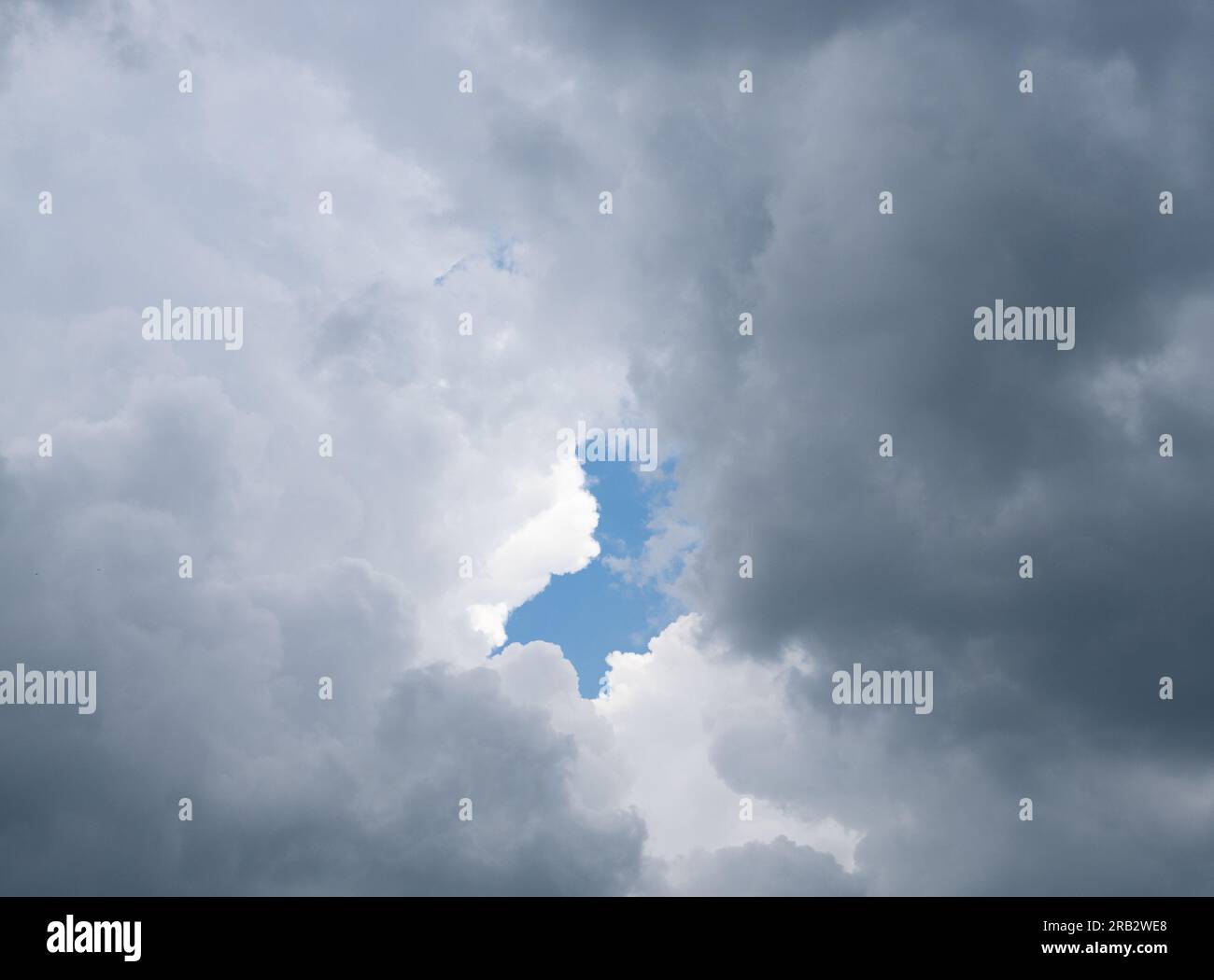 Gray and white cumulus storm clouds with a patch of blue sky ...