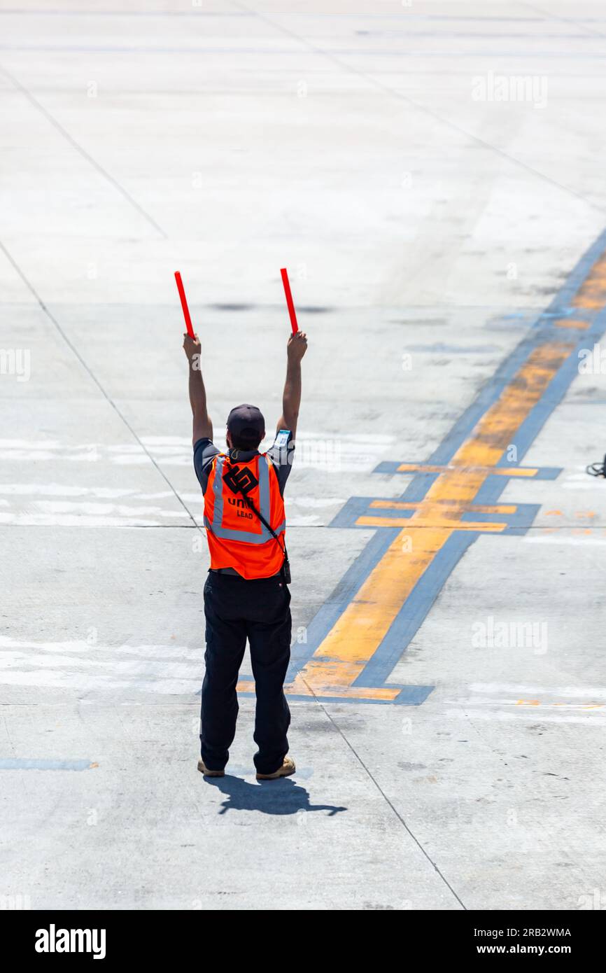 A Unifi Aviation Services marshaller directs an aircraft into a parking ...