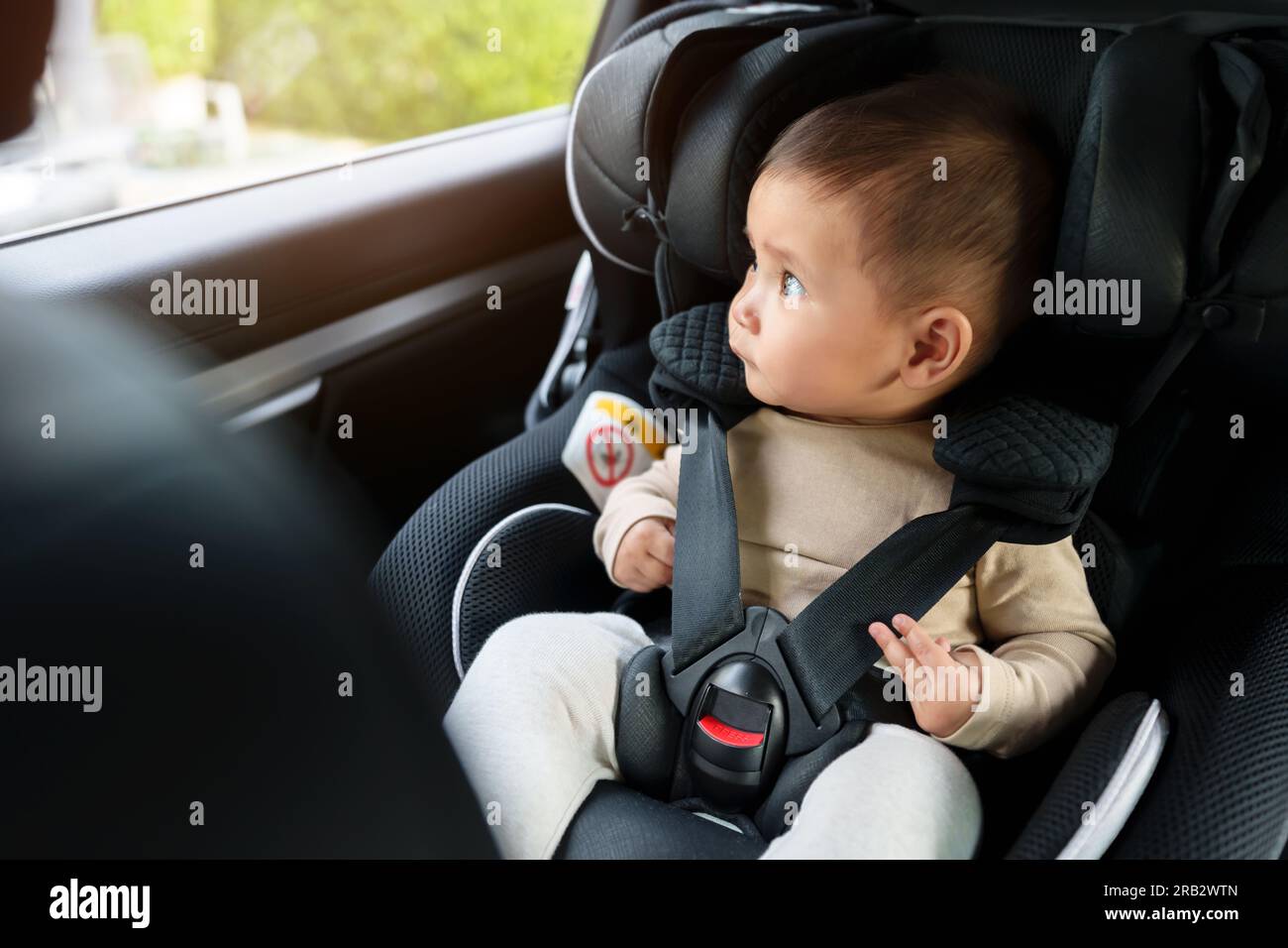 happy infant baby sitting in car seat and looking out of the window ...