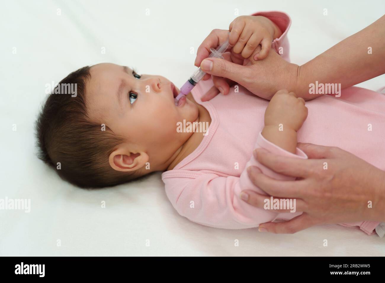 mother feeding a liquid medicine to sick infant baby with a syringe ...