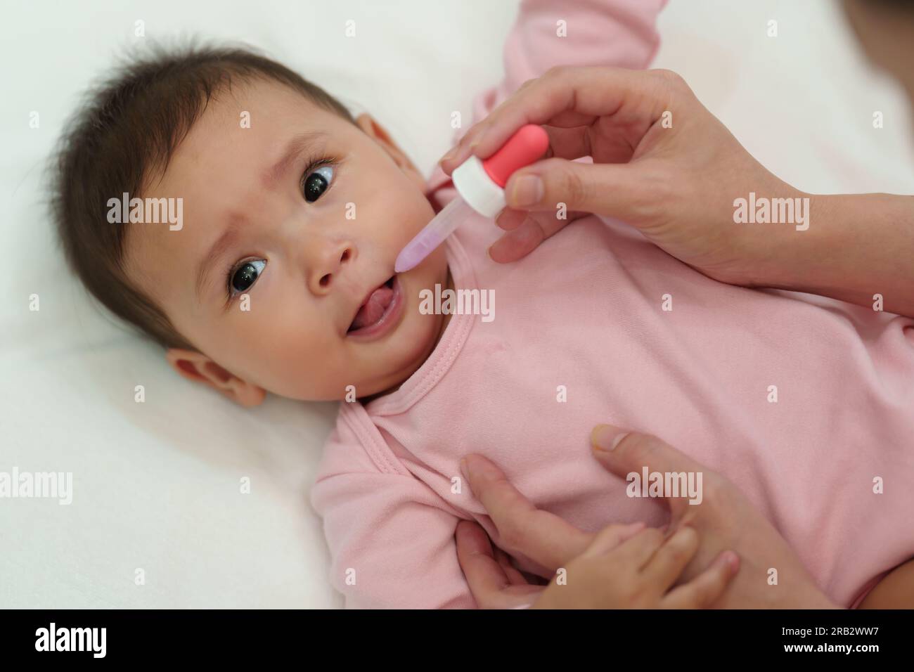 mother feeding a liquid medicine to sick infant baby with dropper Stock ...