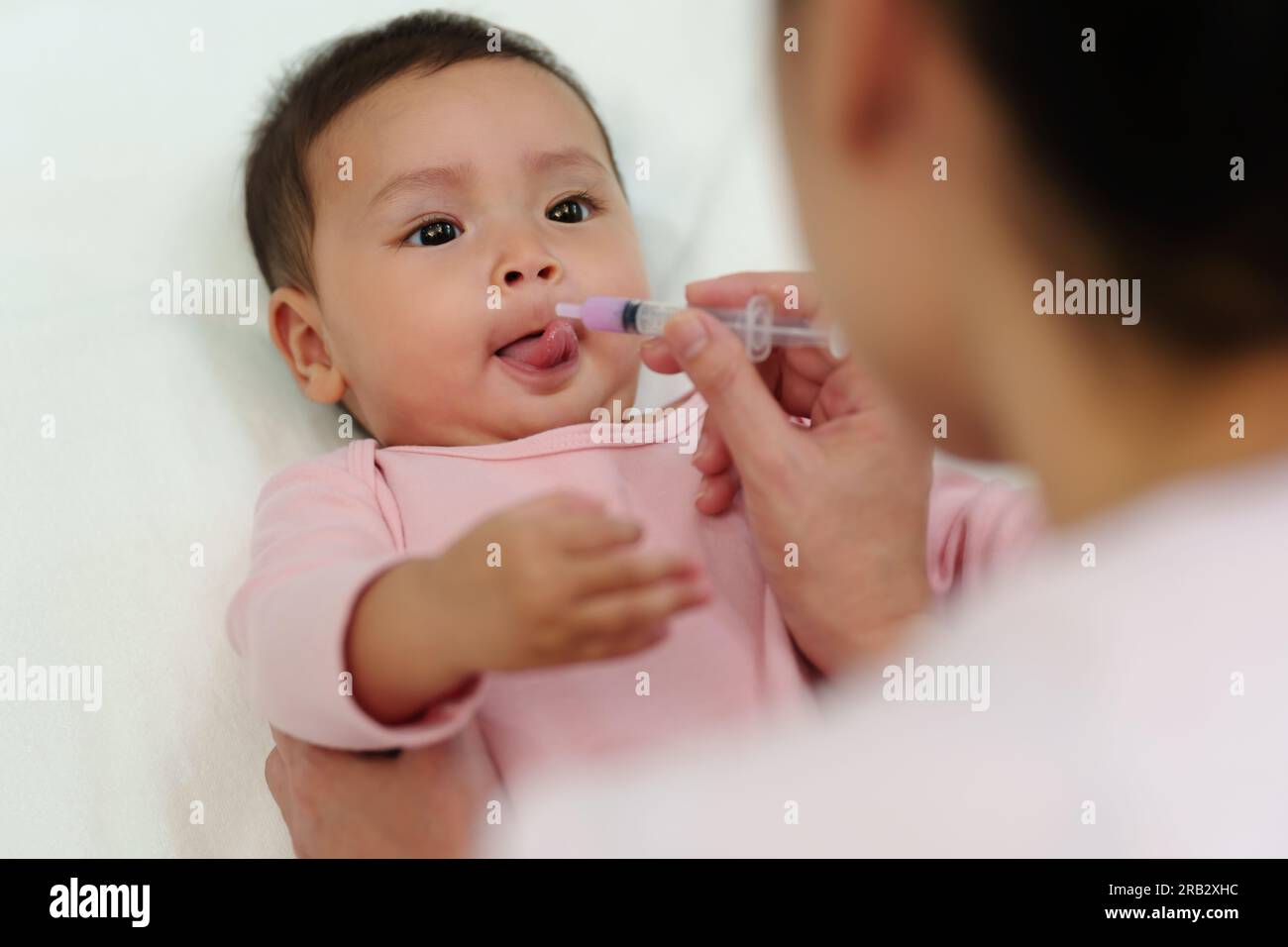 mother feeding a liquid medicine to sick infant baby with a syringe ...