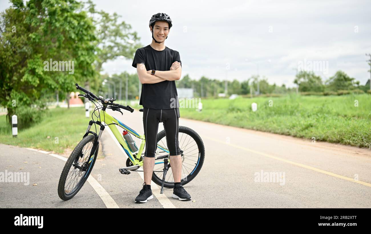 A portrait of a happy and handsome Asian man in sportswear and a bike ...