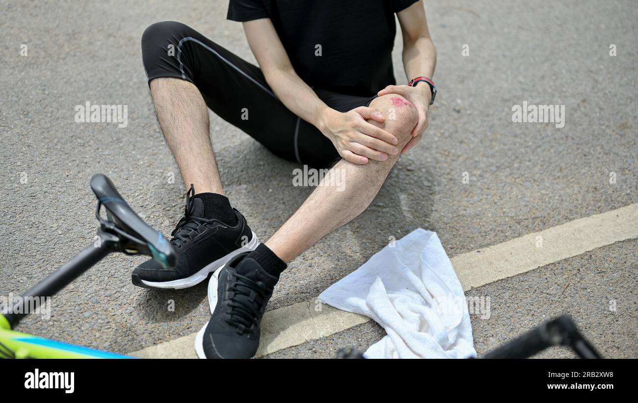Close-up image of an injured male cyclist in sportswear fell off the ...