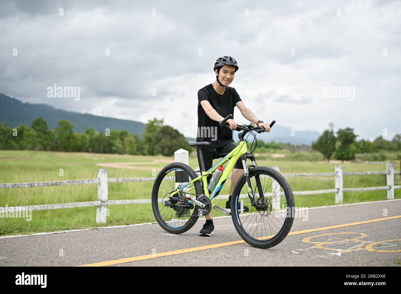 A handsome and happy young Asian man in sportswear and a bike helmet ...