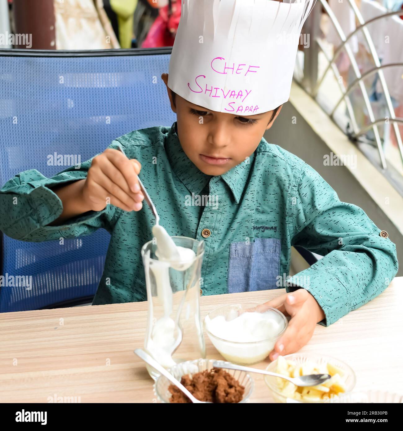 Cute Indian chef boy preparing sundae dish as a part of non fire ...