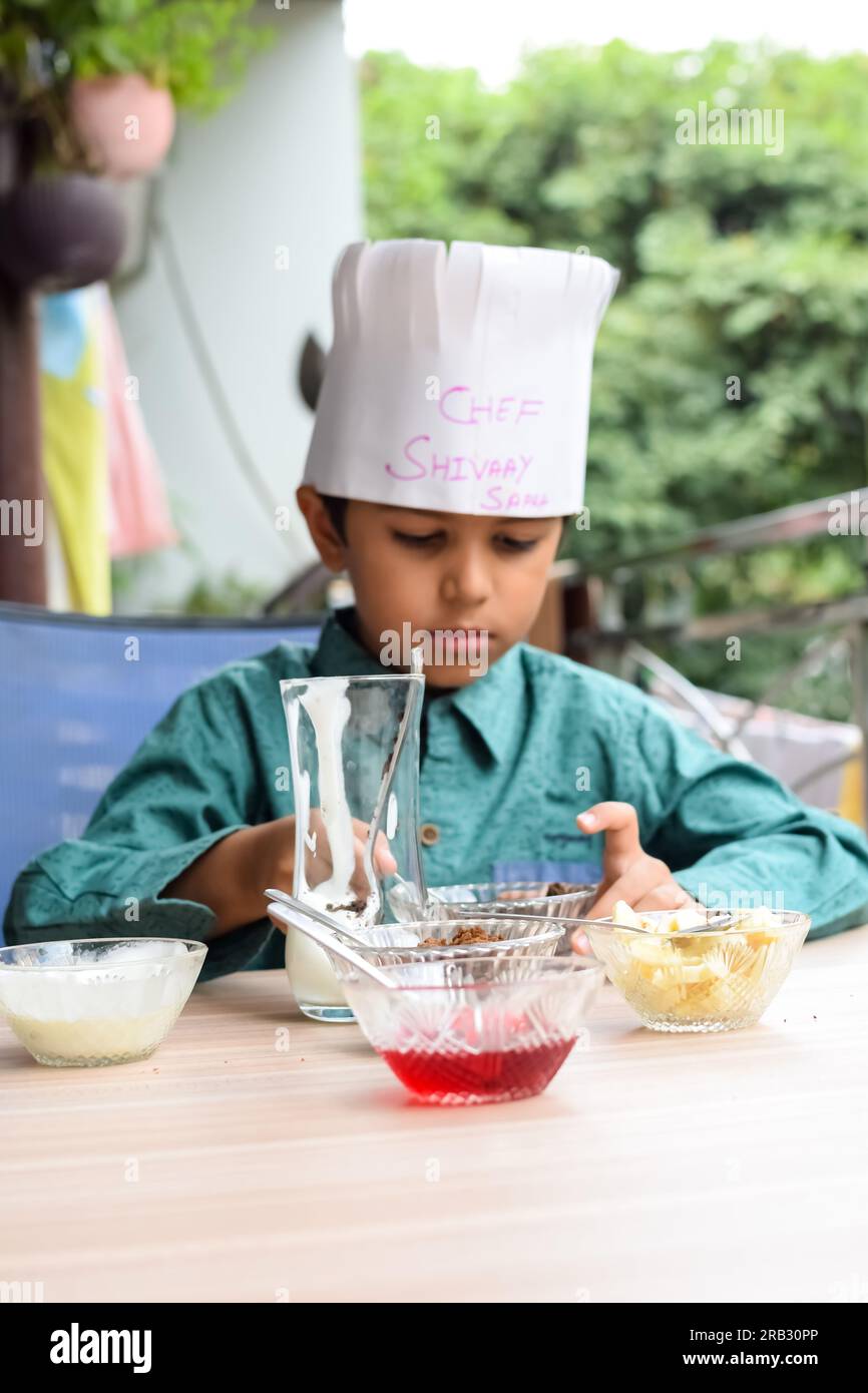 Cute Indian chef boy preparing sundae dish as a part of non fire ...
