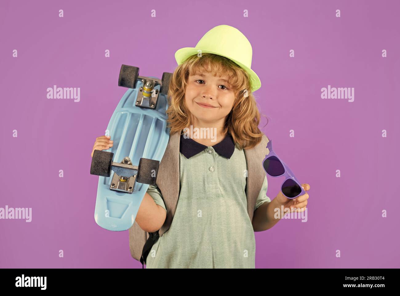 Child boy holding longboard on violet isolated background. Kid with ...