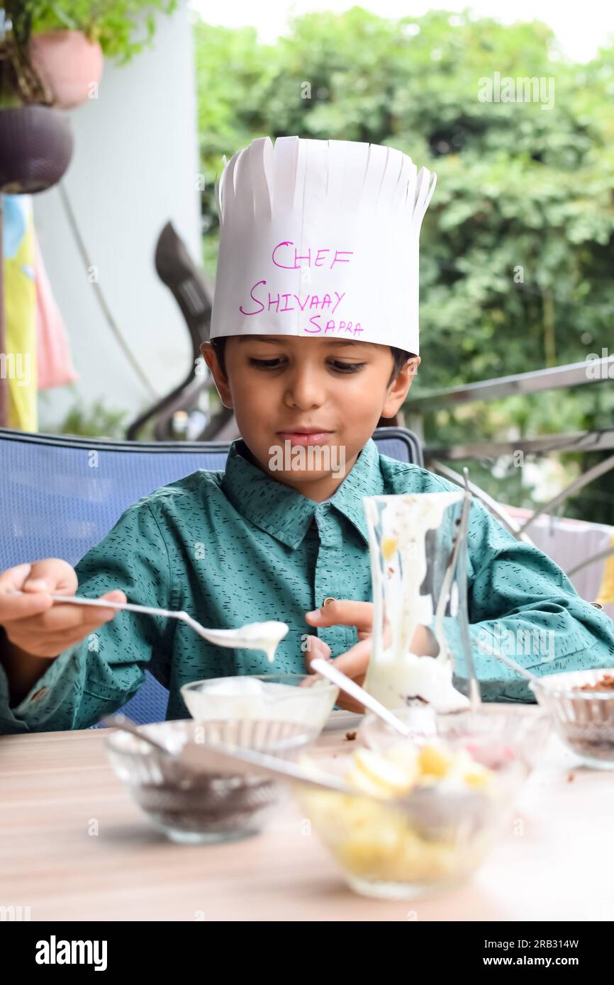 Cute Indian chef boy preparing sundae dish as a part of non fire ...