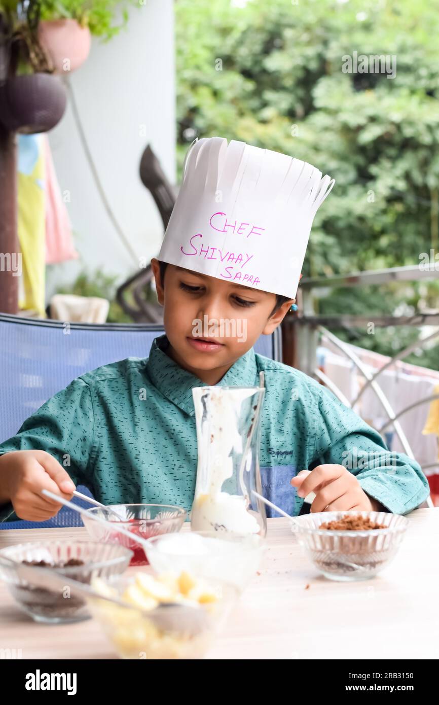 Cute Indian chef boy preparing sundae dish as a part of non fire ...