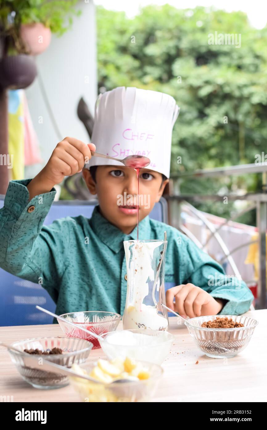 Cute Indian chef boy preparing sundae dish as a part of non fire ...