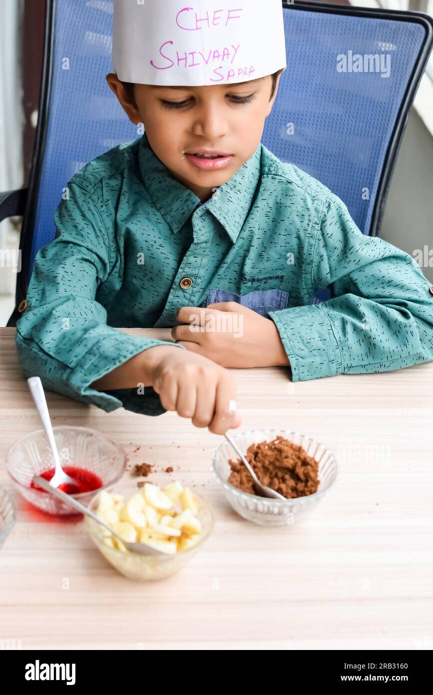 Cute Indian chef boy preparing sundae dish as a part of non fire ...
