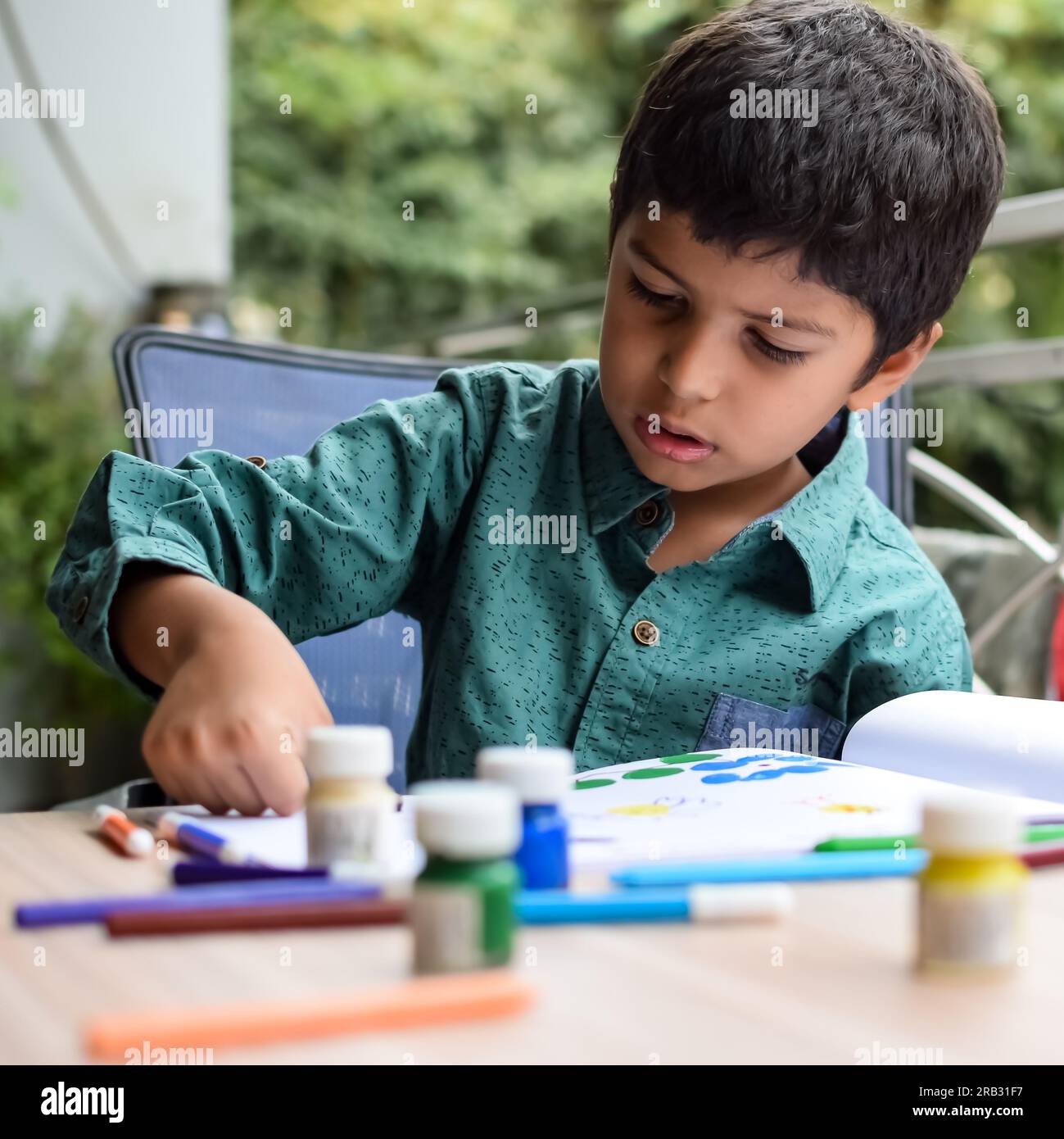 Smart Indian little boy perform thumb painting with different colourful ...