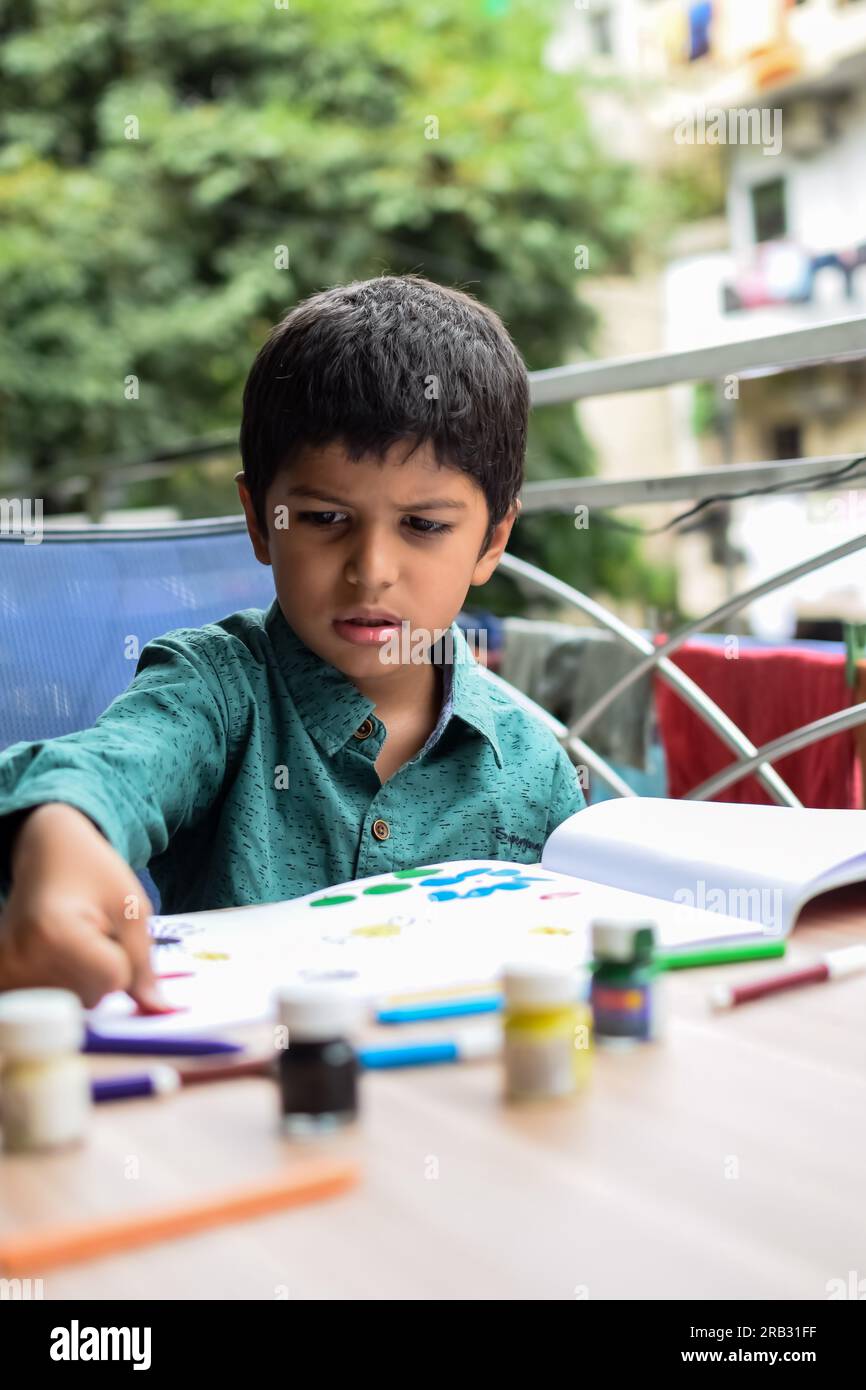 Smart Indian little boy perform thumb painting with different colourful ...