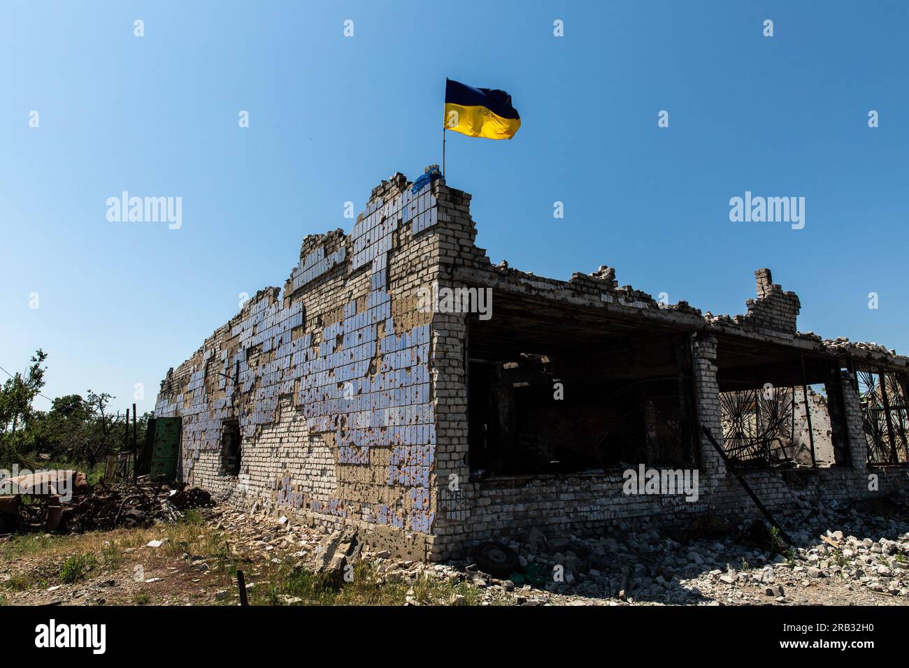 A Ukrainian flag seen and the top of the ruins of a building in ...