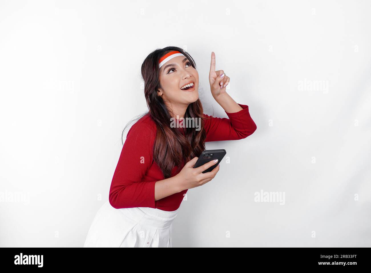 A Happy Asian Woman Wearing Headband Holding Her Phone And Pointing