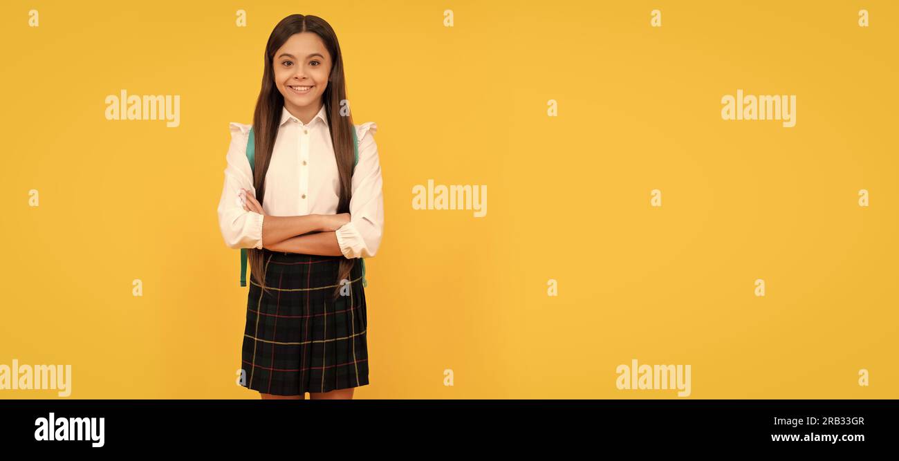 happy teen girl in school uniform full length crossed hands on yellow ...