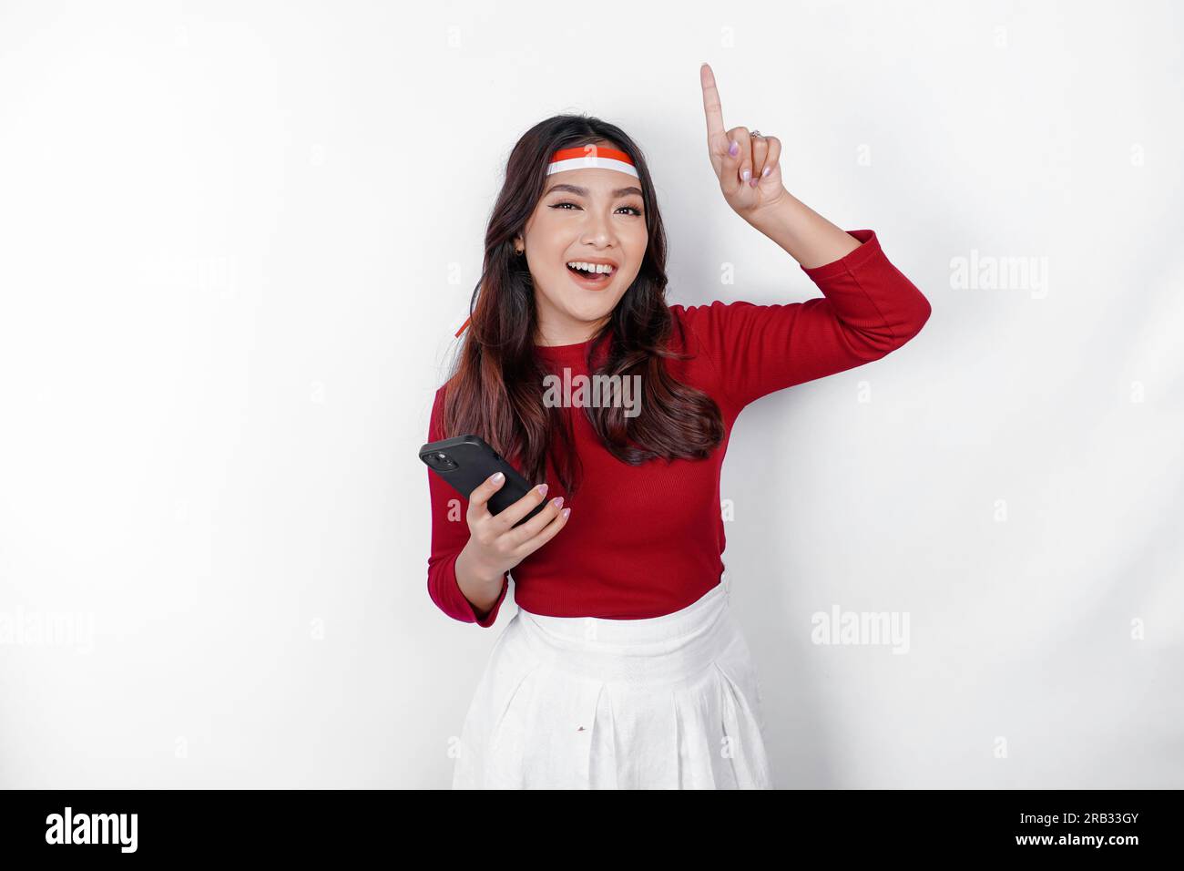A Happy Asian Woman Wearing Headband Holding Her Phone And Pointing