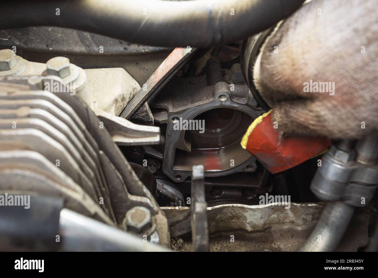 An auto mechanic sands and removes dirt from a part before installing a ...