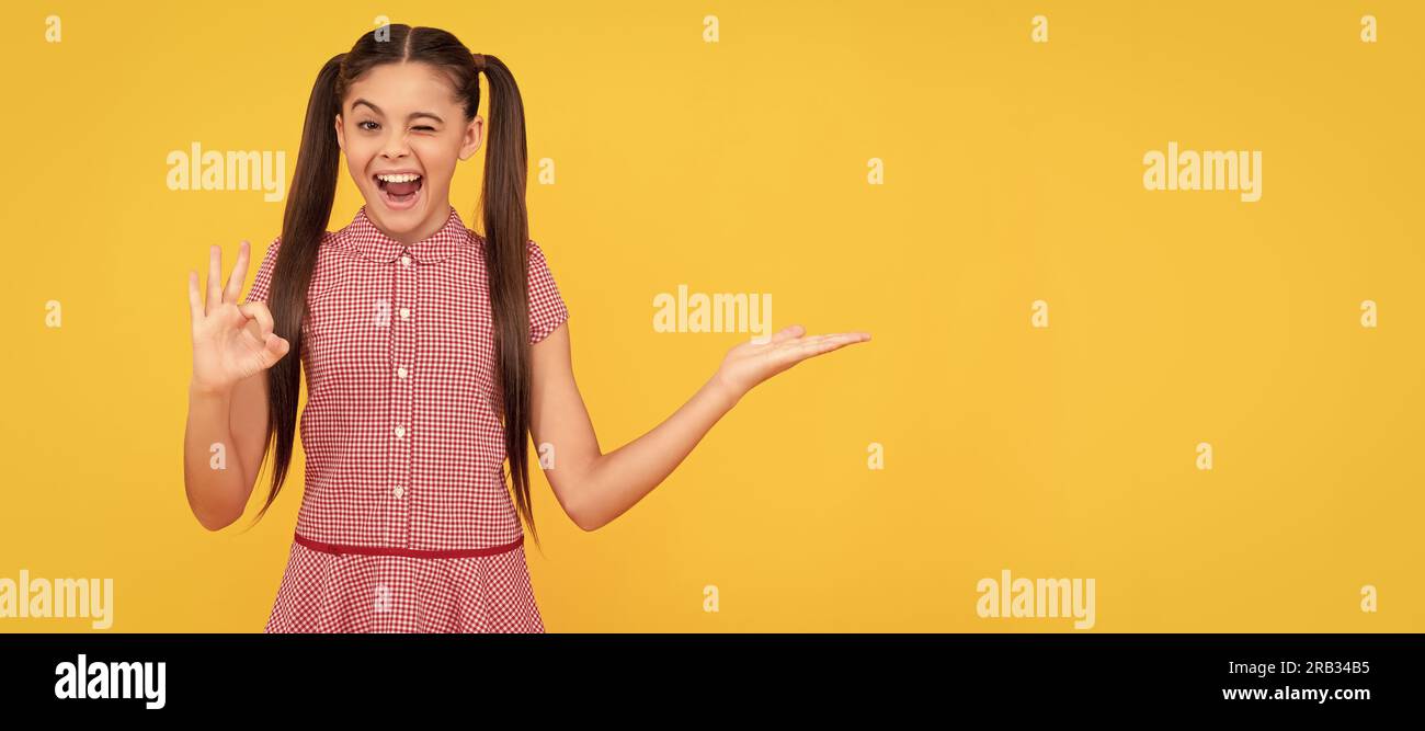 winking kid presenting product, copy space. ok. teen girl advertising ...