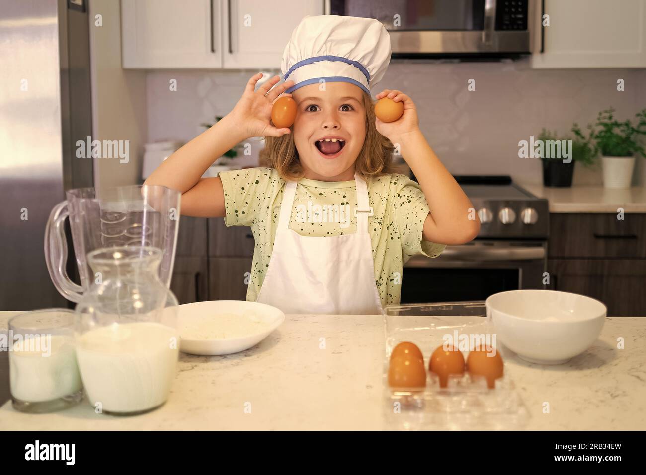 Child chef cook. Funny child stand at kitchen table have fun baking ...