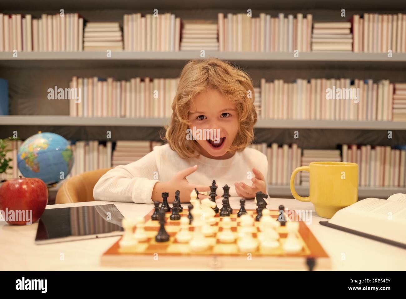 Little child play chess in classroom. Kid playing board game. Thinking ...