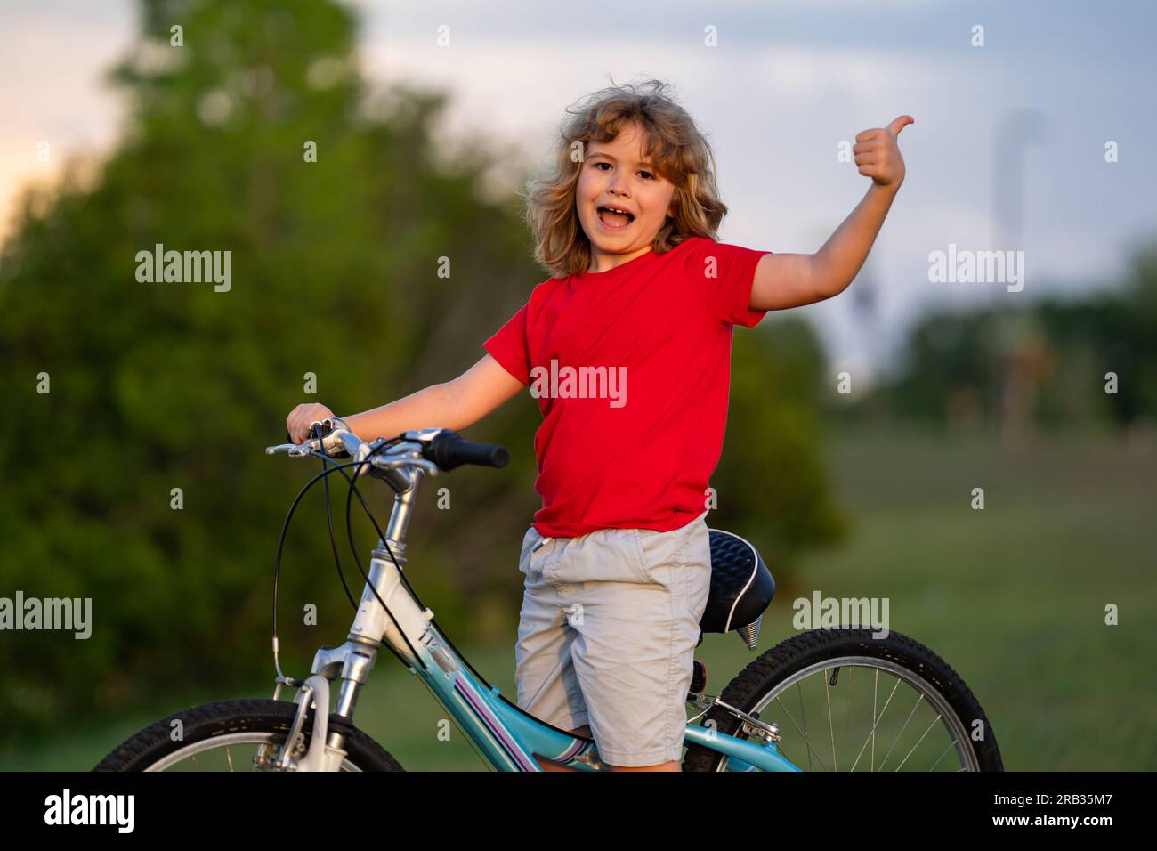 Little kid boy riding a bike in summer park. Child drive a bike on a ...