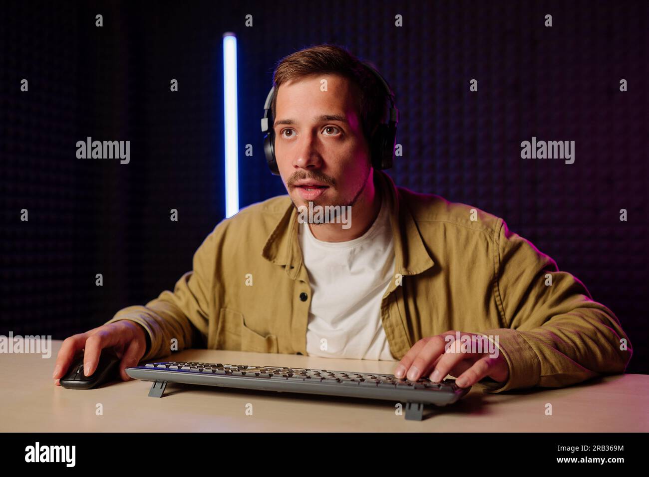 Concentrated gamer sitting at night at the computer and playing ...