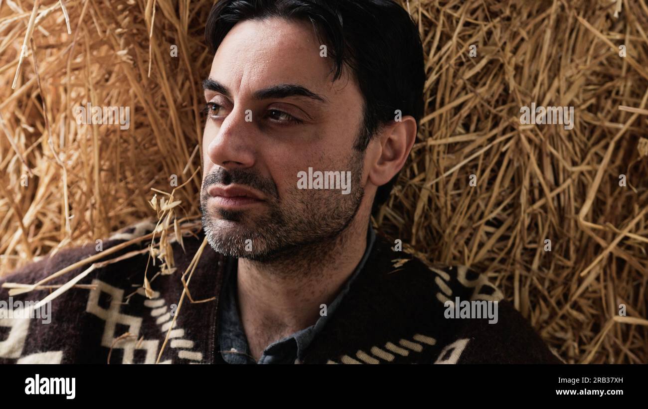 Tired cowboy leaning on hay bale Stock Photo - Alamy