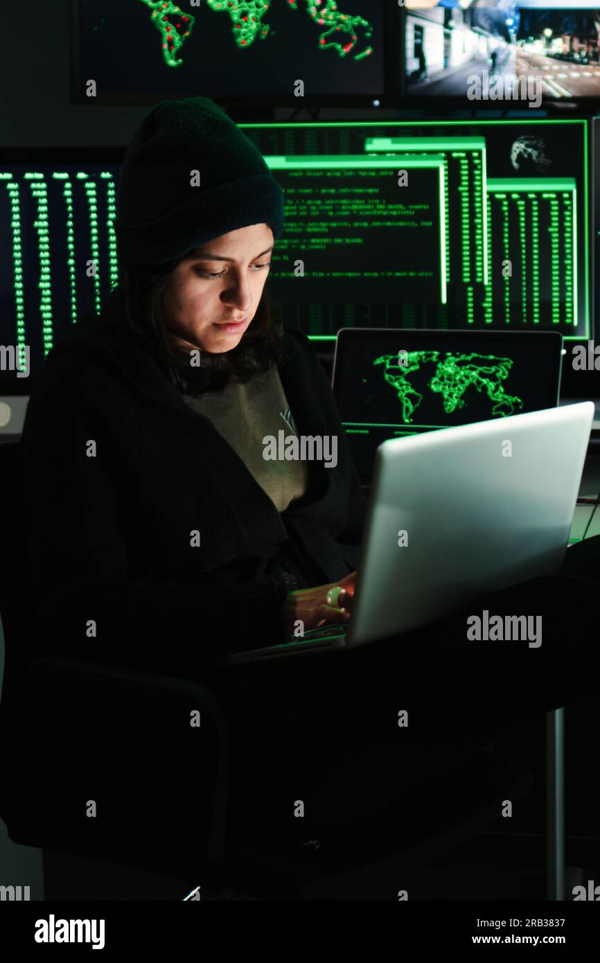 Vertical portrait of informatic hacker female typing code on laptop, at ...