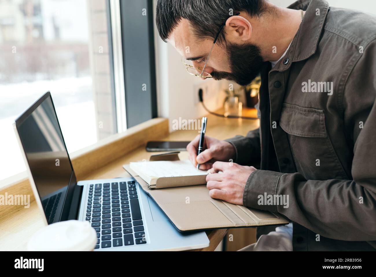 A caucasian man write in notepad on a cafe. work process. A man with a ...