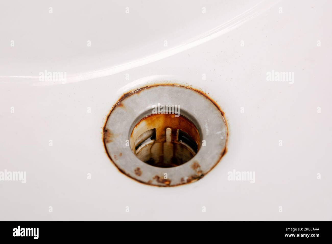 Dirty and rusty washbasin, close up view. Metal drain hole with red ...