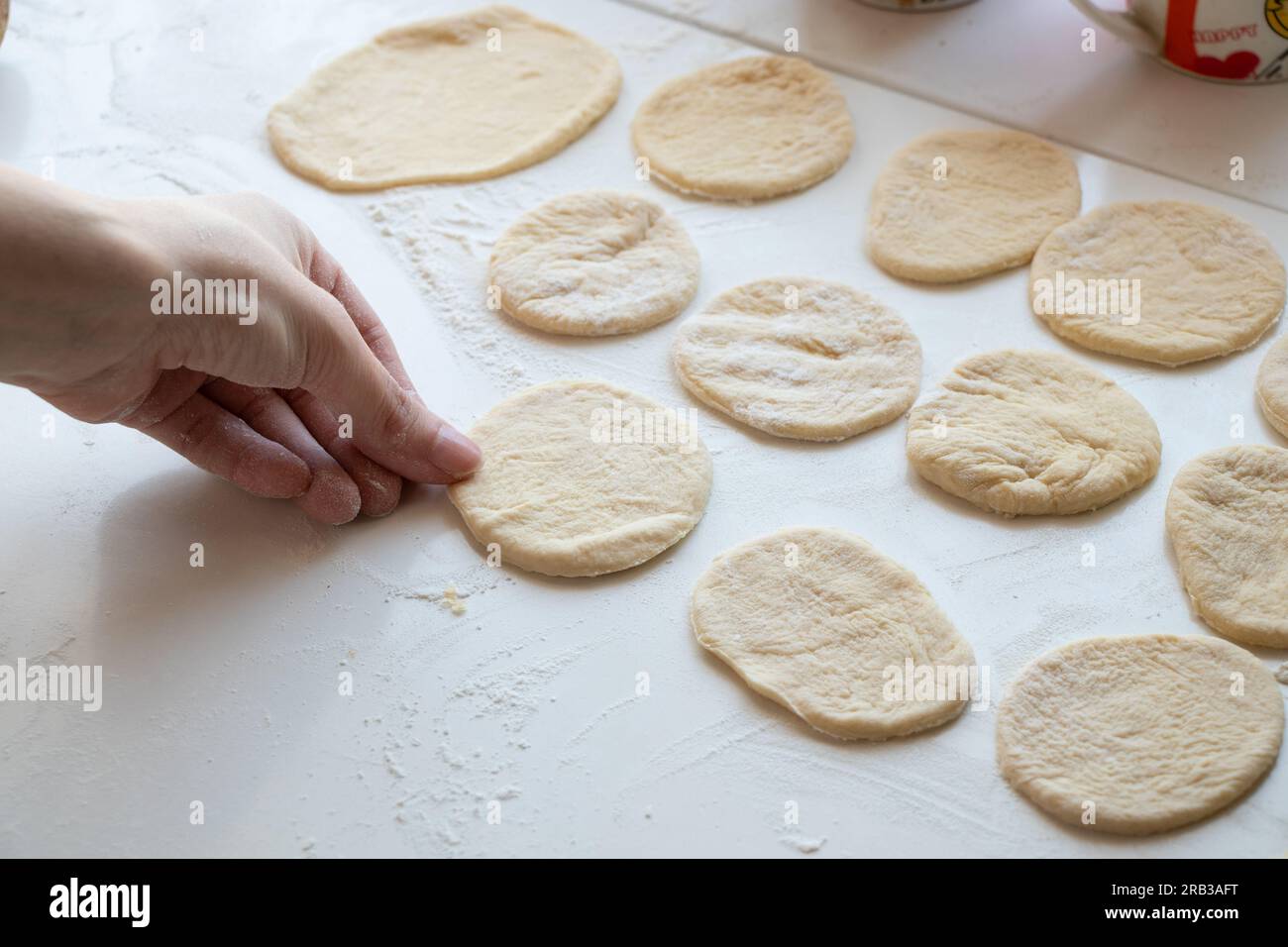 female hands knead raw dough on a white table in the kitchen, dough ...