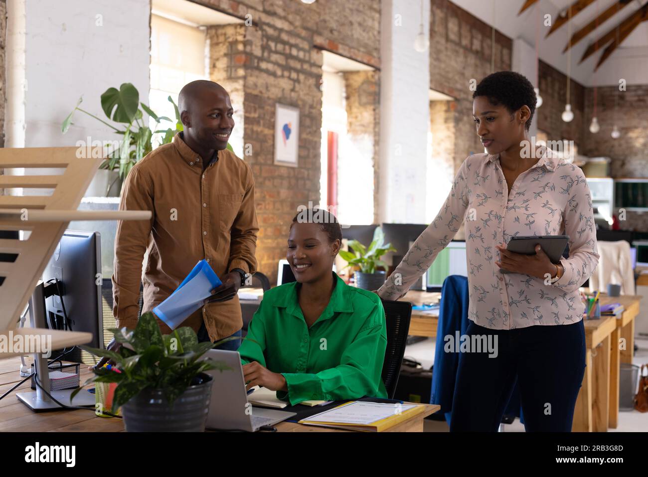 Happy african american colleagues using computer and talking in ...