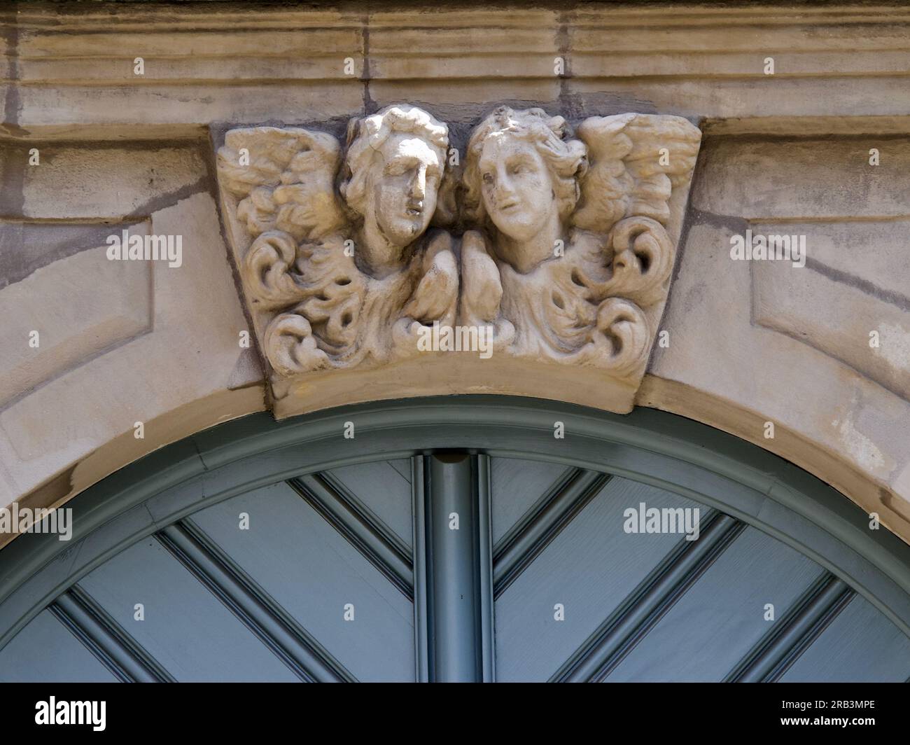 Stone building with blue door and door lintel decorated with two angel ...