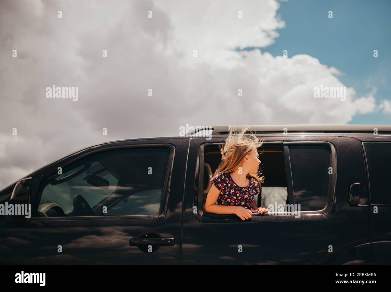 Girl sticking head out window with hair blown Stock Photo - Alamy