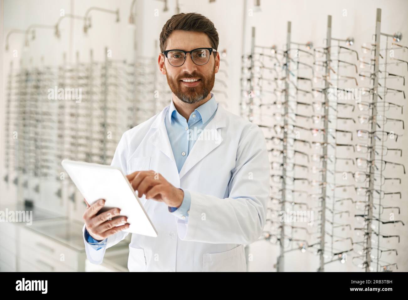 Male optician with digital tablet on background of shop windows with ...