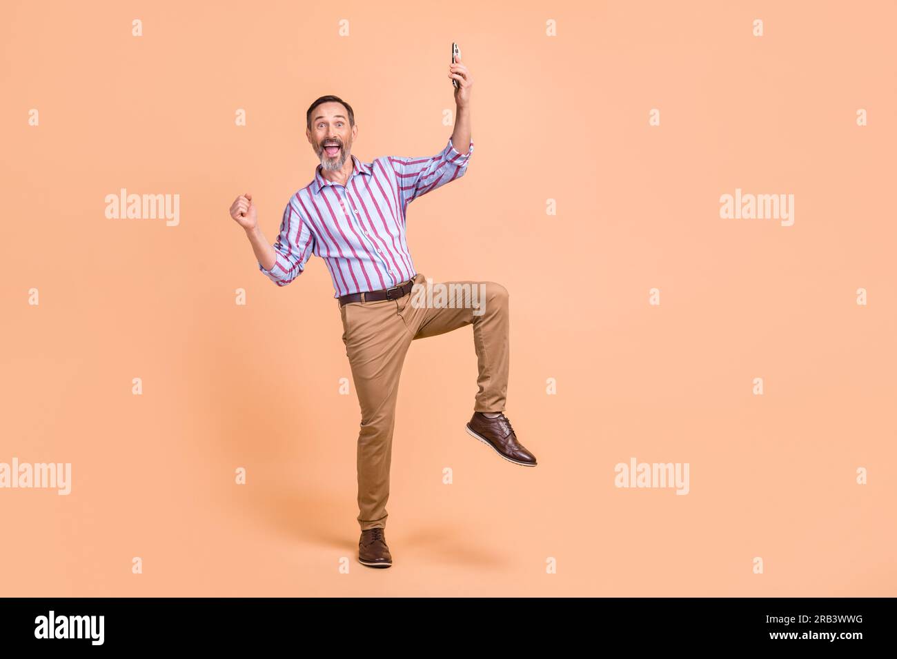 Full length portrait of delighted crazy man hold smart phone raise fist ...