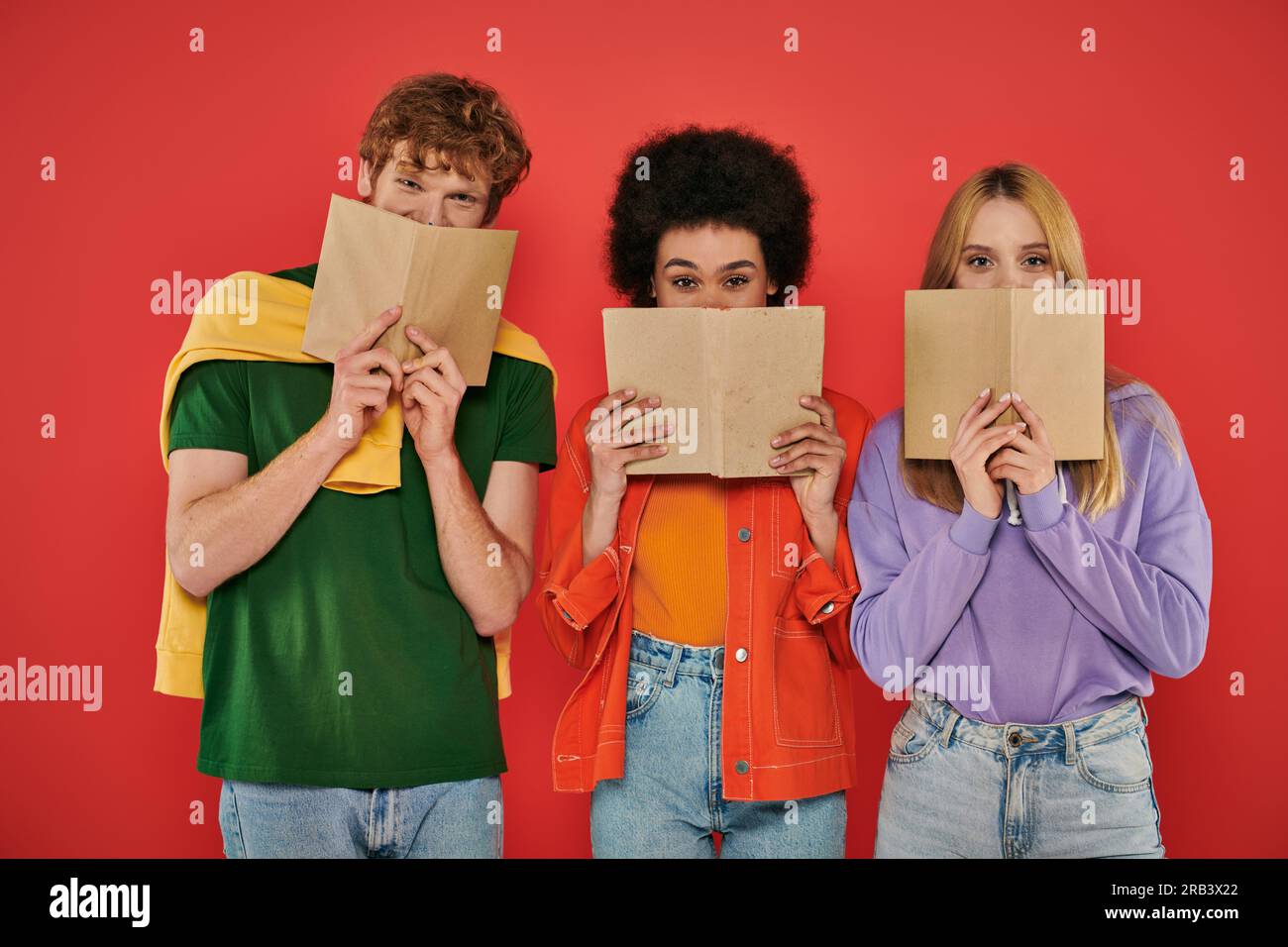 polygamy concept, three interracial people covering faces with books on ...