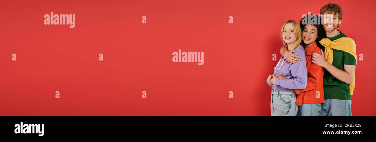 polygamy concept, three interracial lovers hugging on coral background ...