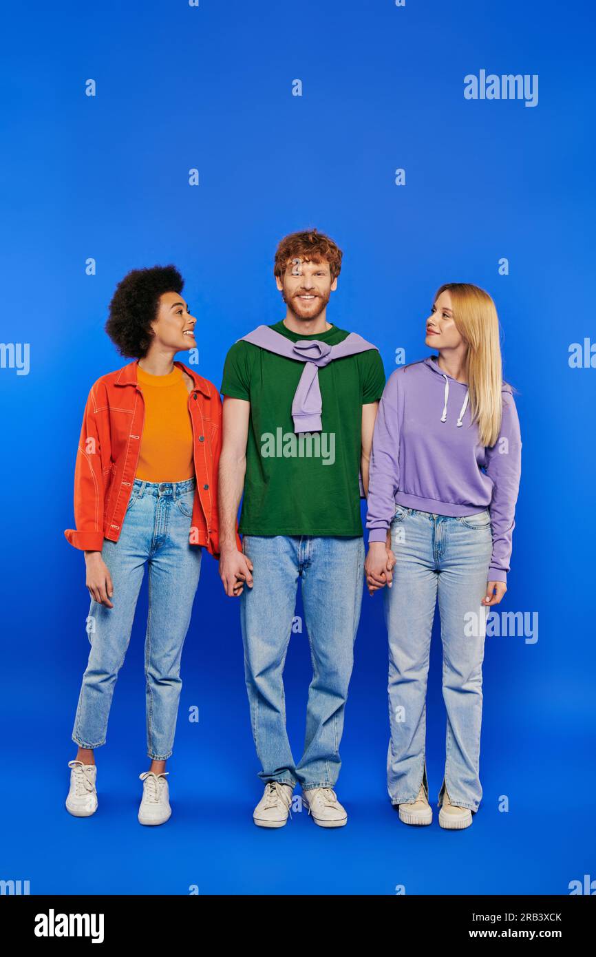 polyamory three people, young man and women holding hands on blue ...