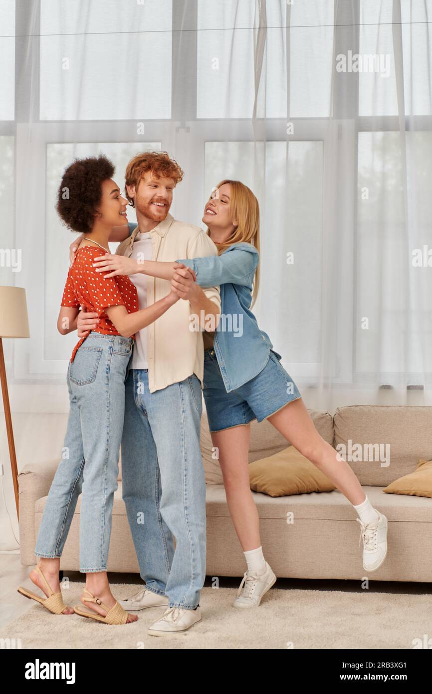 alternative family, happy multicultural women hugging redhead man in ...