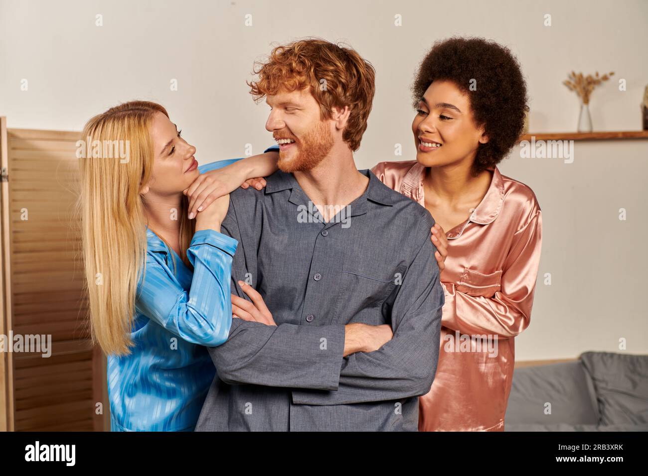 polyamory lovers, happy man with folded arms near interracial women in ...